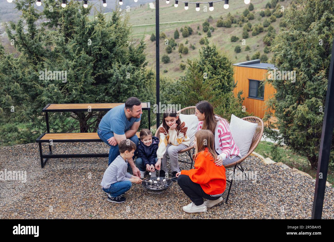 Big happy family roasting mashmallows outdoors. Young mom, dad, three ...
