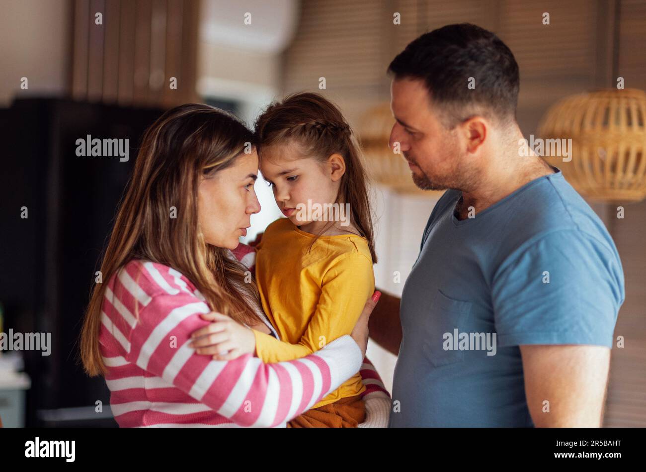 Young parents comfort their cute daughter. Beautiful woman hugs and ...