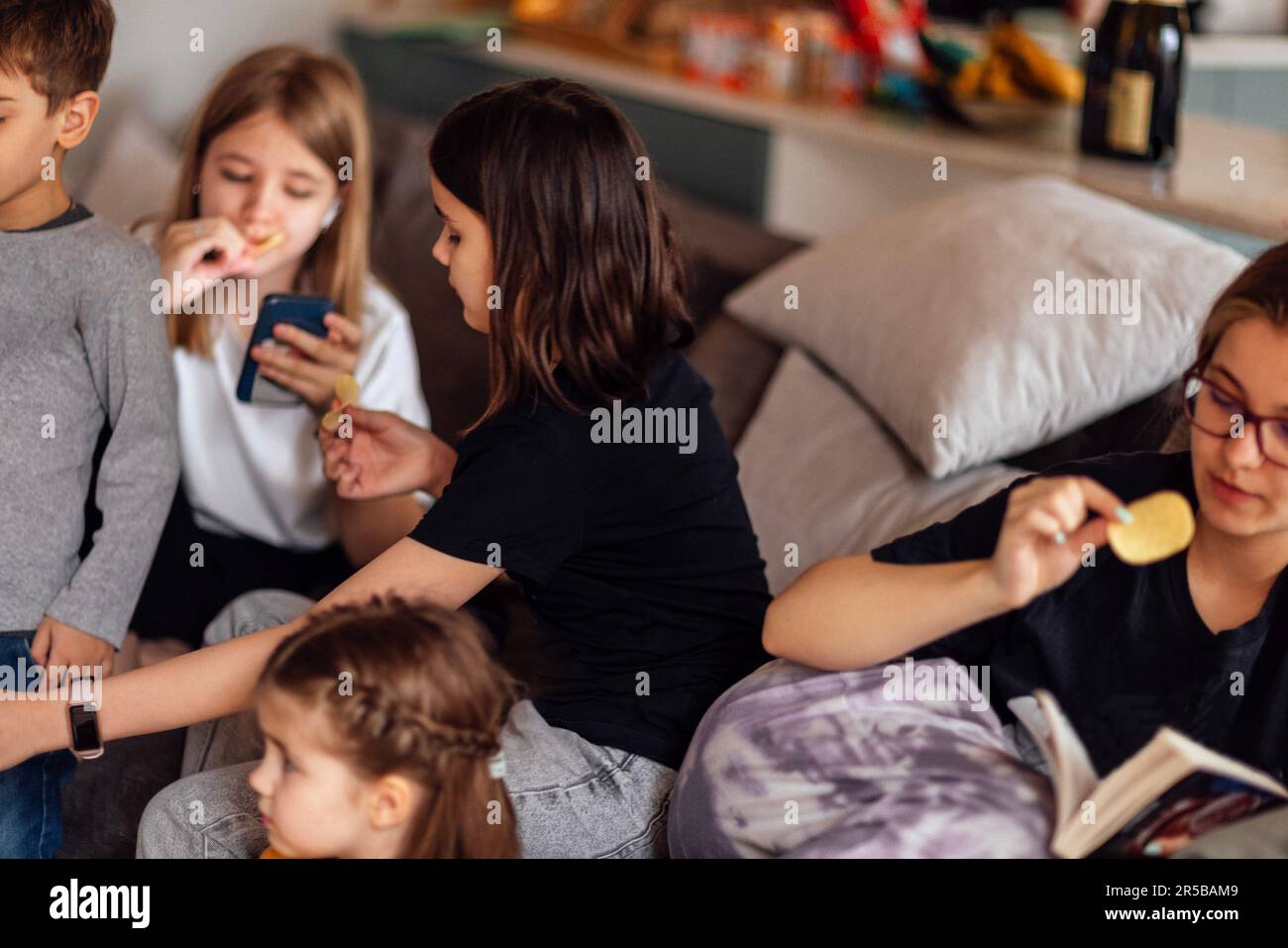 Large family spends time together and snacks on chips. Two female ...
