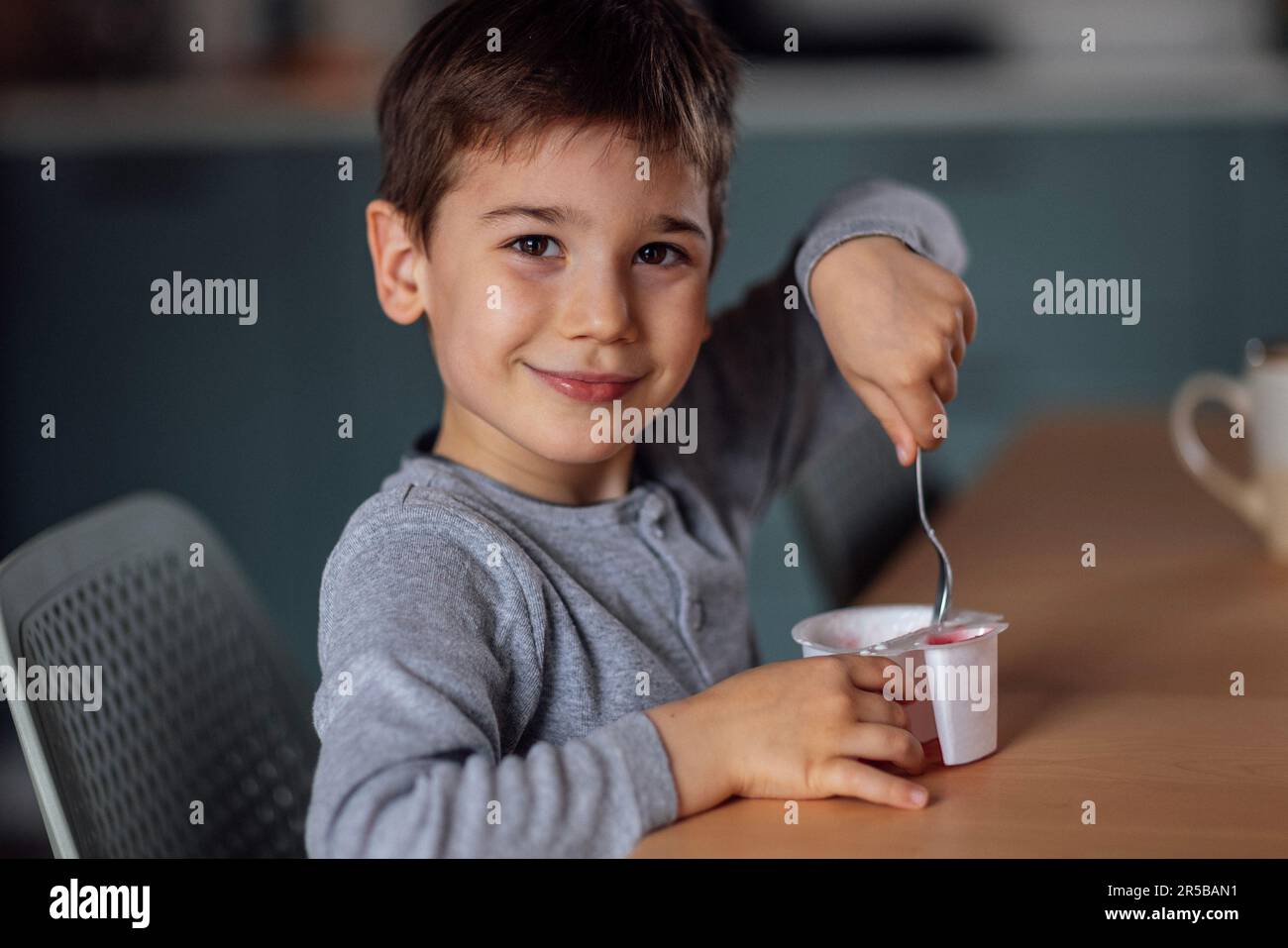 Close up of portrait of cute little boy eats delicious yogurt or ...
