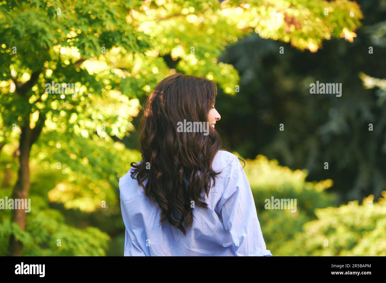 Outdoor portrait of happy young woman enjoying environment in green ...