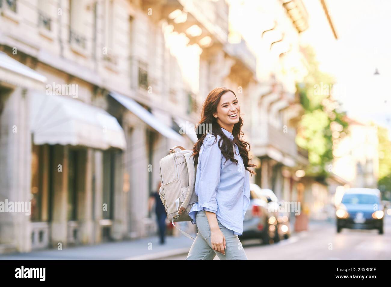 Outdoor portrait of beautiful young woman walking down the street ...