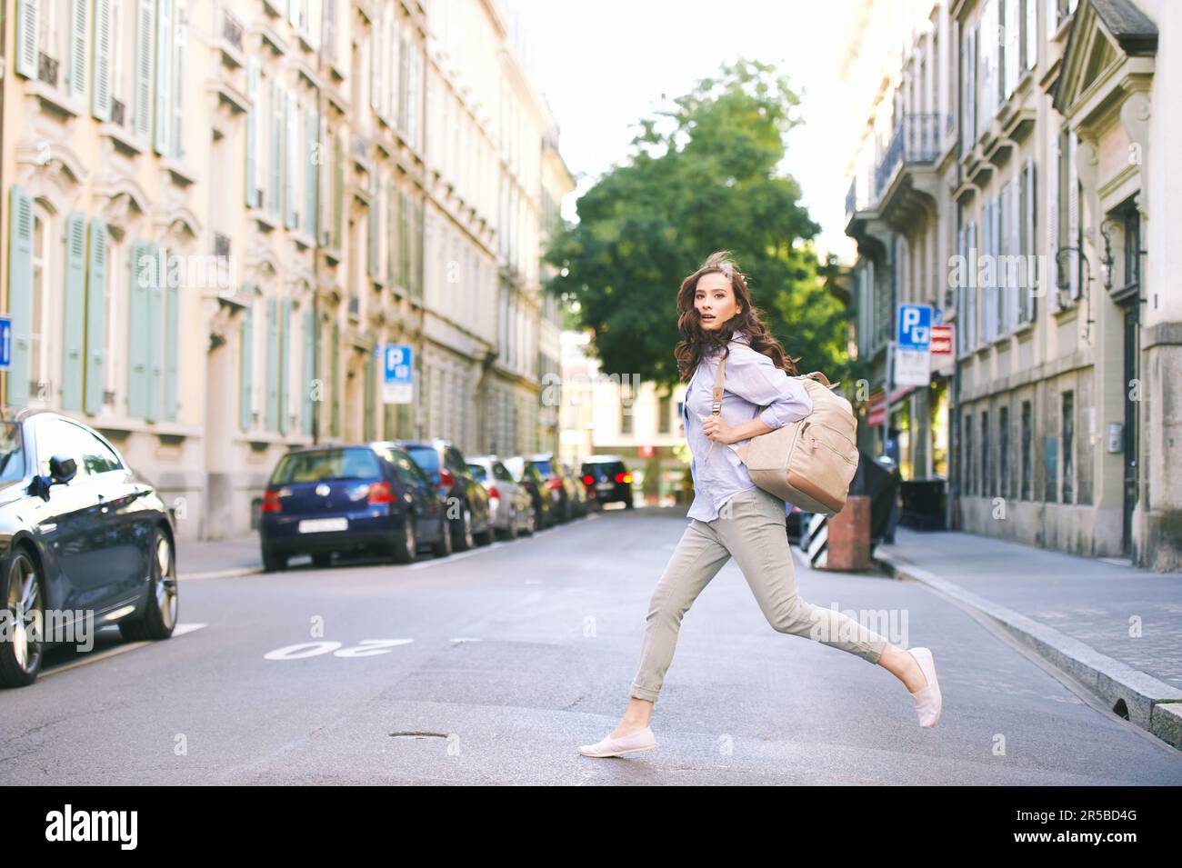 Outdoor portrait of beautiful young woman walking down the street ...