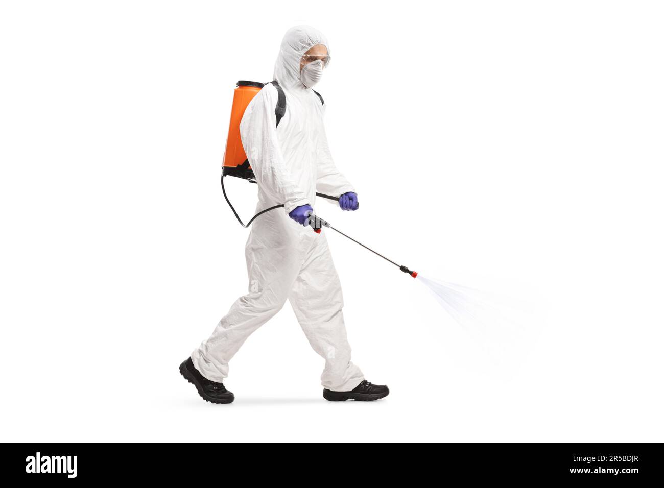 Pest professional in a hazmat suit walking and spraying a sanitizer ...