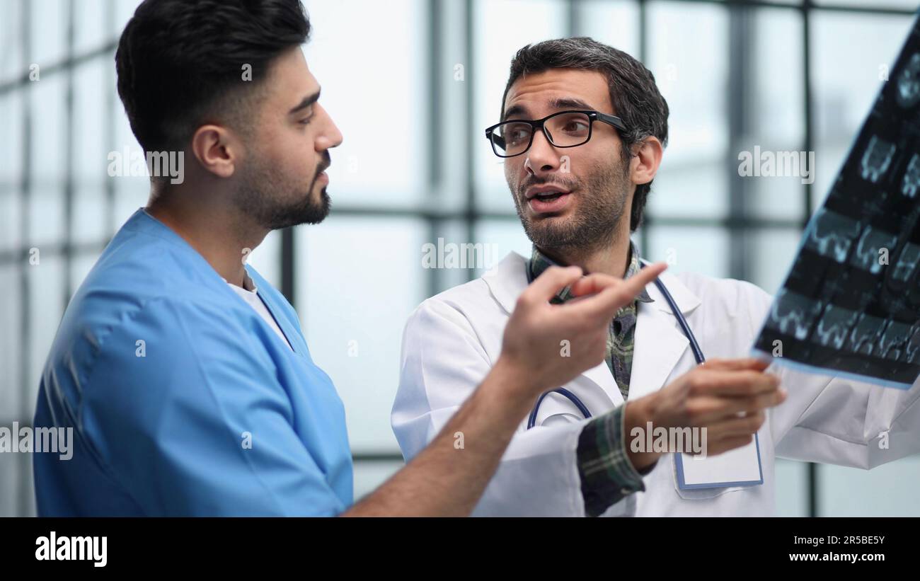 Doctors and an intern examine an X-ray of a patient. MRI scans of brain ...