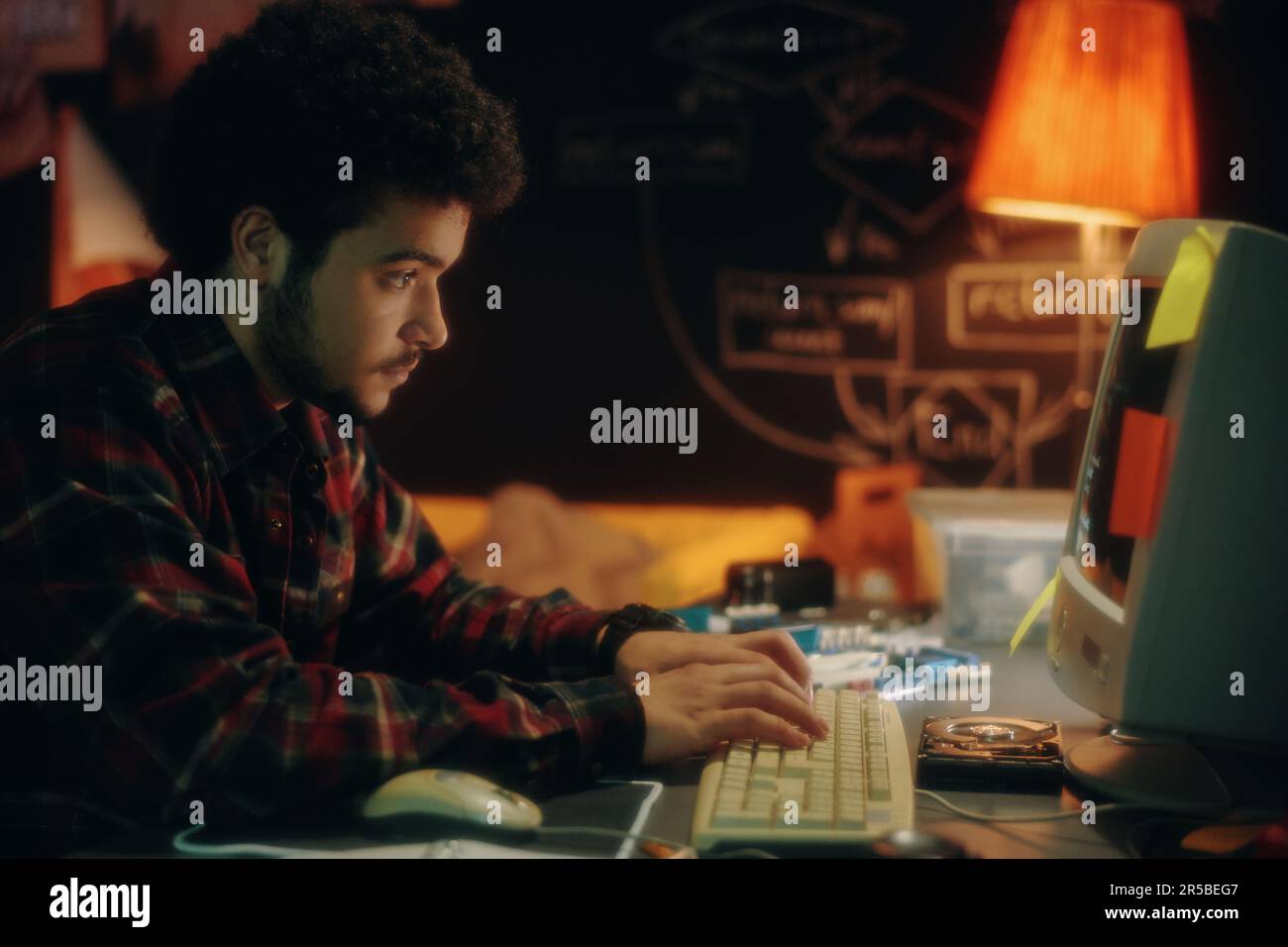 Side view of young man typing codes on keyboard on computer to develop ...