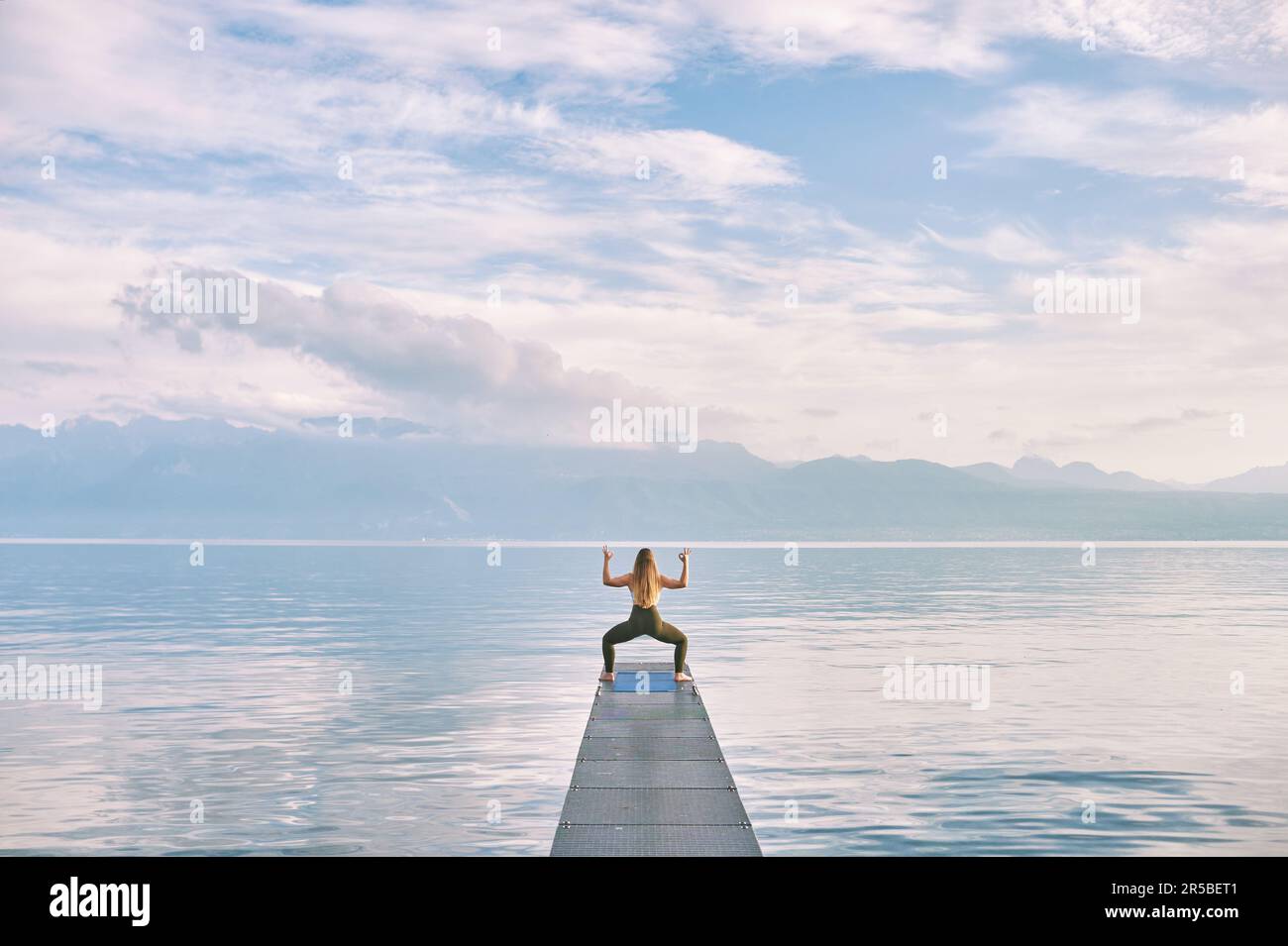 Outdoor portrait of young beautiful woman practicing yoga on dock by ...