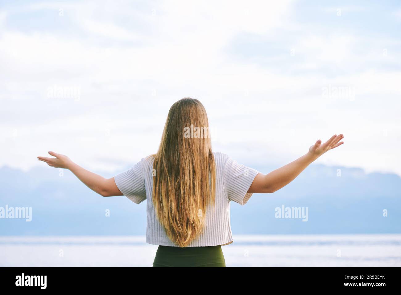Young blond woman with arms wide open enjoy landscape of cloudy ...