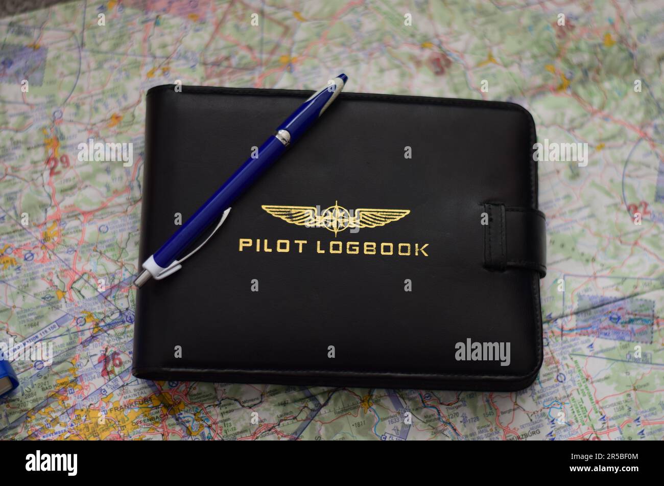 A pilot's logbook lies open with a pen resting on the page, beside a ...