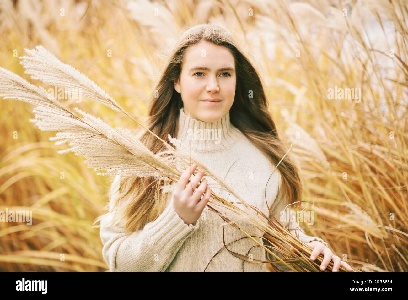 Fall portrait of young pretty girl posing outside with pampas grass ...