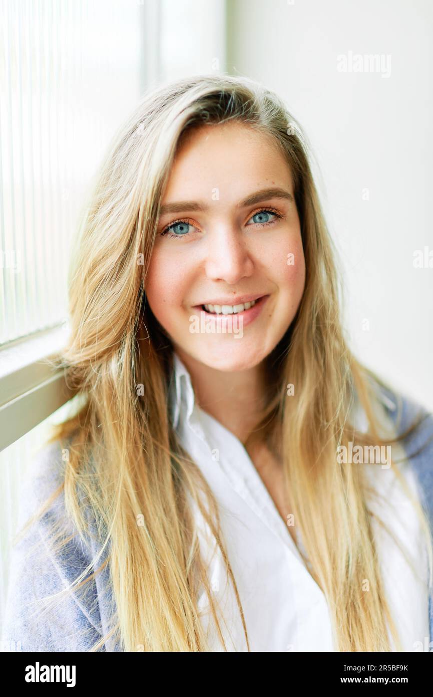 Close up portrait of young 20 year old girl posing next to window, long healthy blond hair Stock ...
