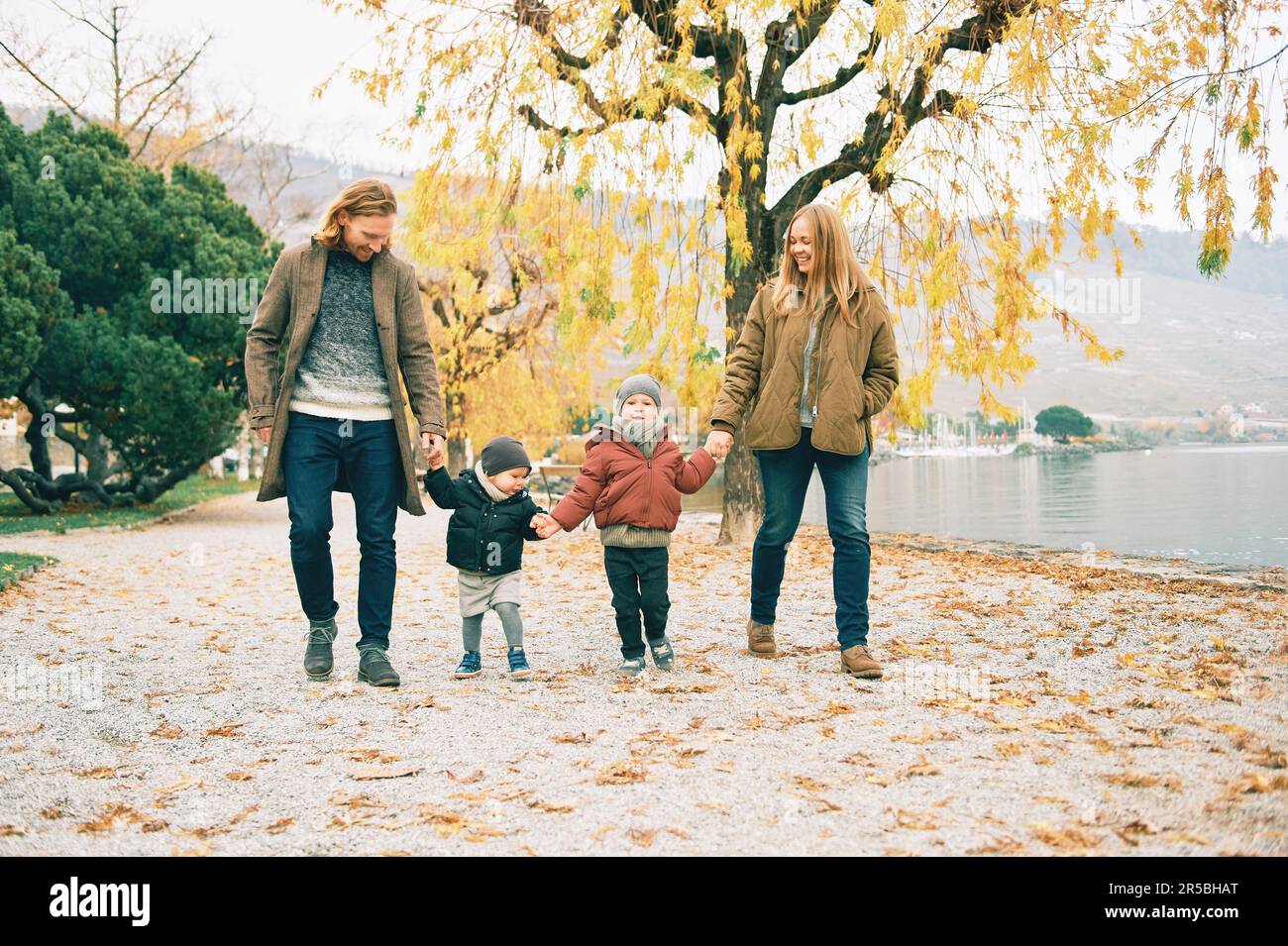 Outdoor portrait of young happy family of four, mother and father ...