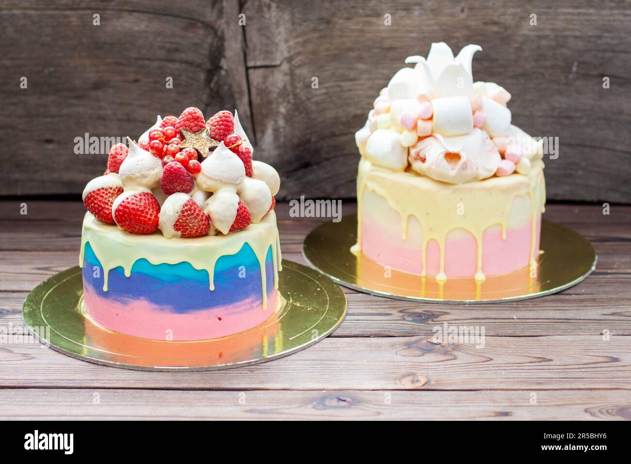 Two colorful cakes. The pink and blue one with melted white chocolate ...
