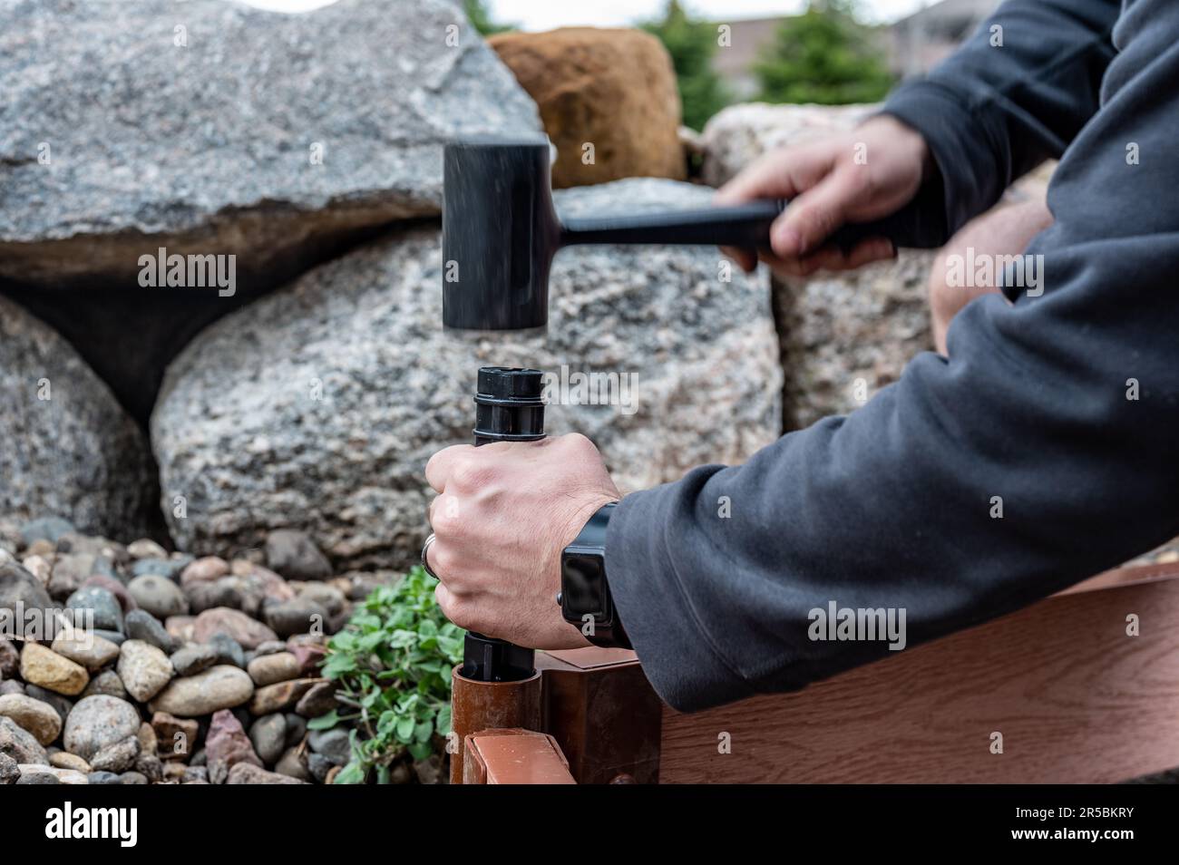 Actively driving a border stake with a rubber mallet to assemble a ...