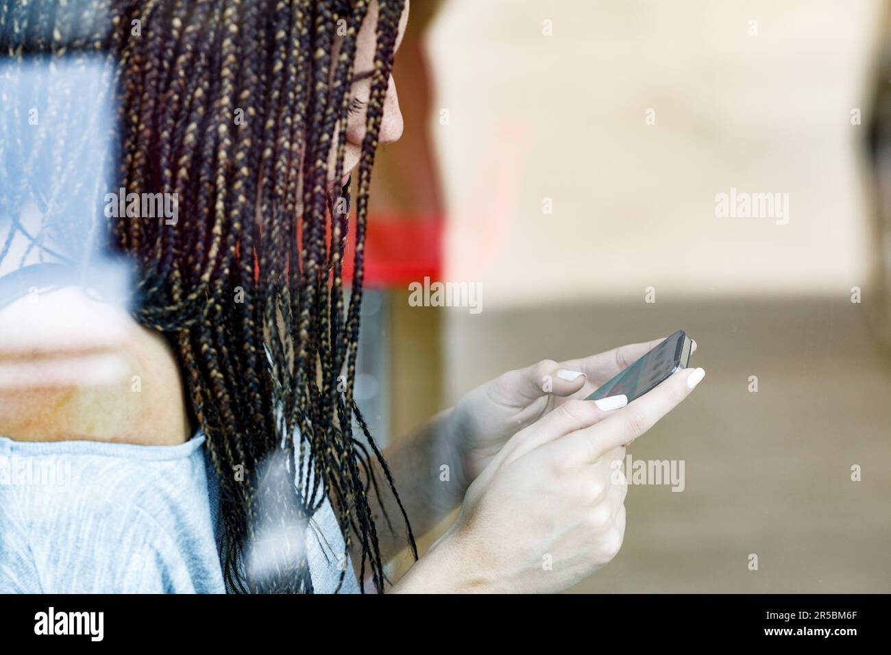 Trapped inside, a young woman with box braids stares out of a window ...