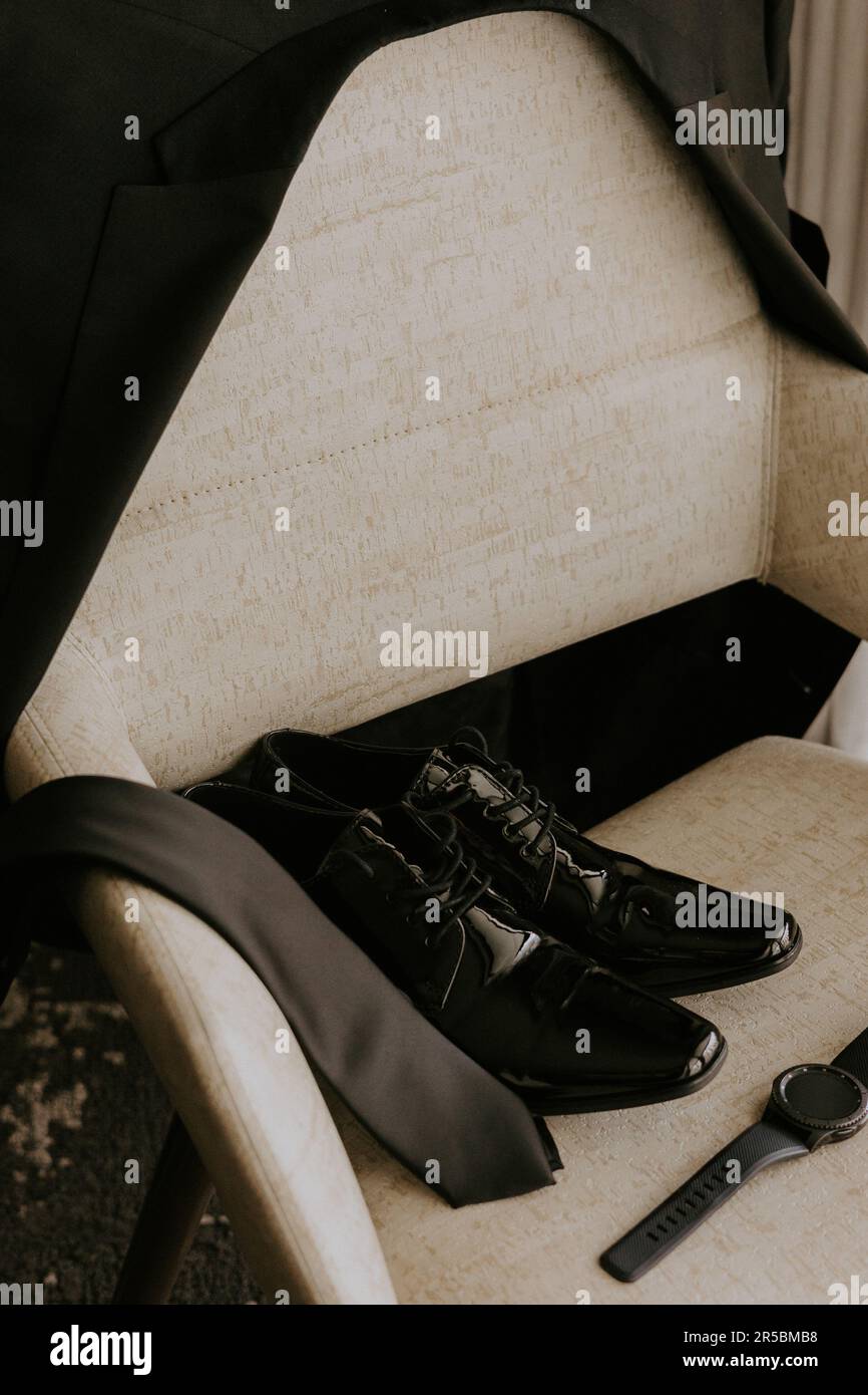 An empty leather chair with two ties draped over the back and a silver ...