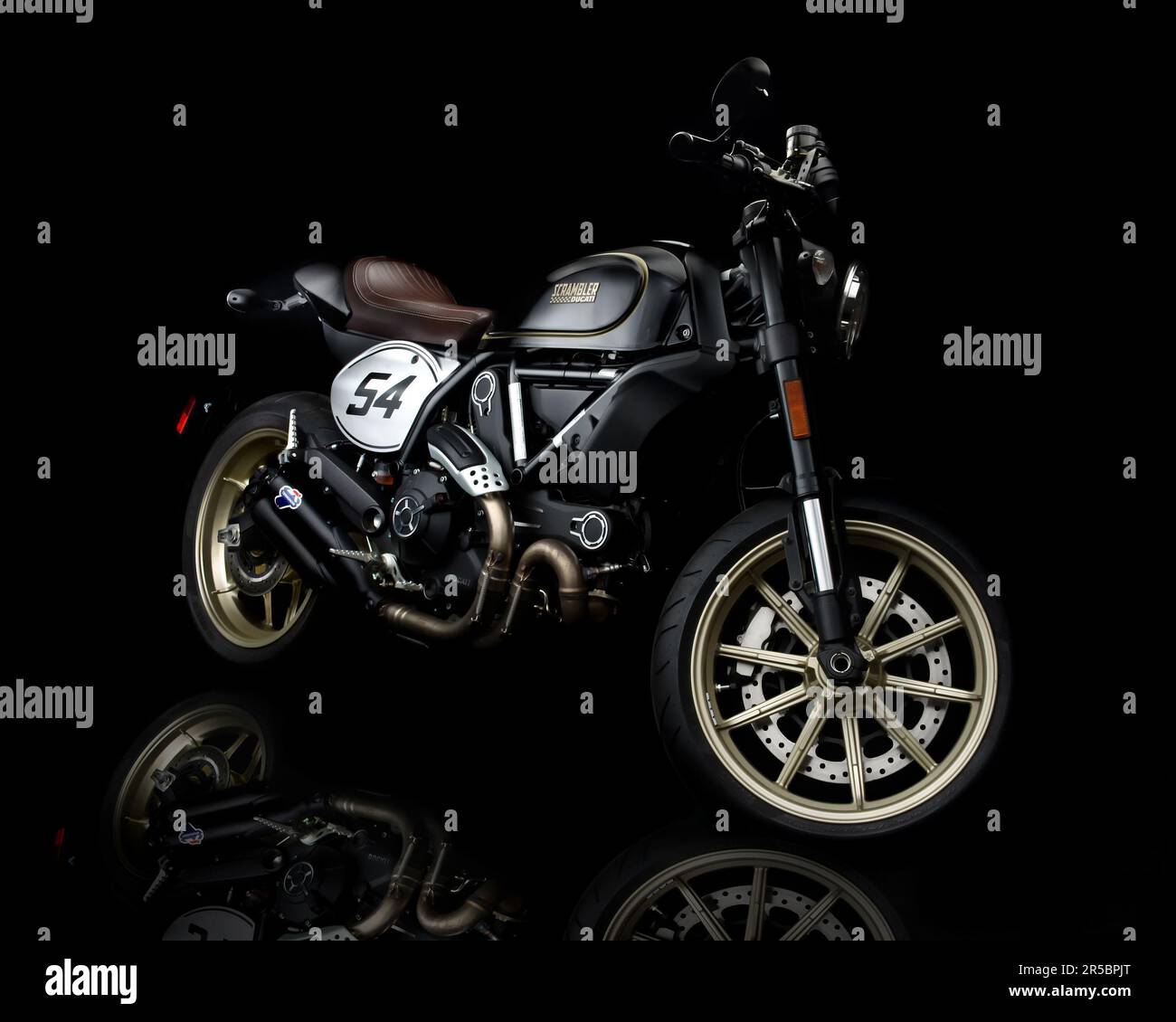 An isolated black motorcycle with golden spoke details is pictured ...