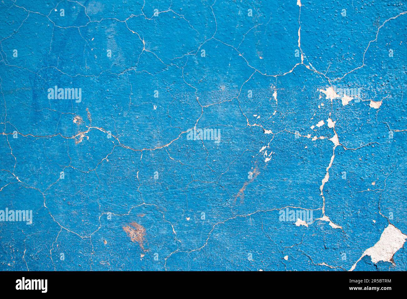 This image features a blue and white wall with cracking paint, the ...