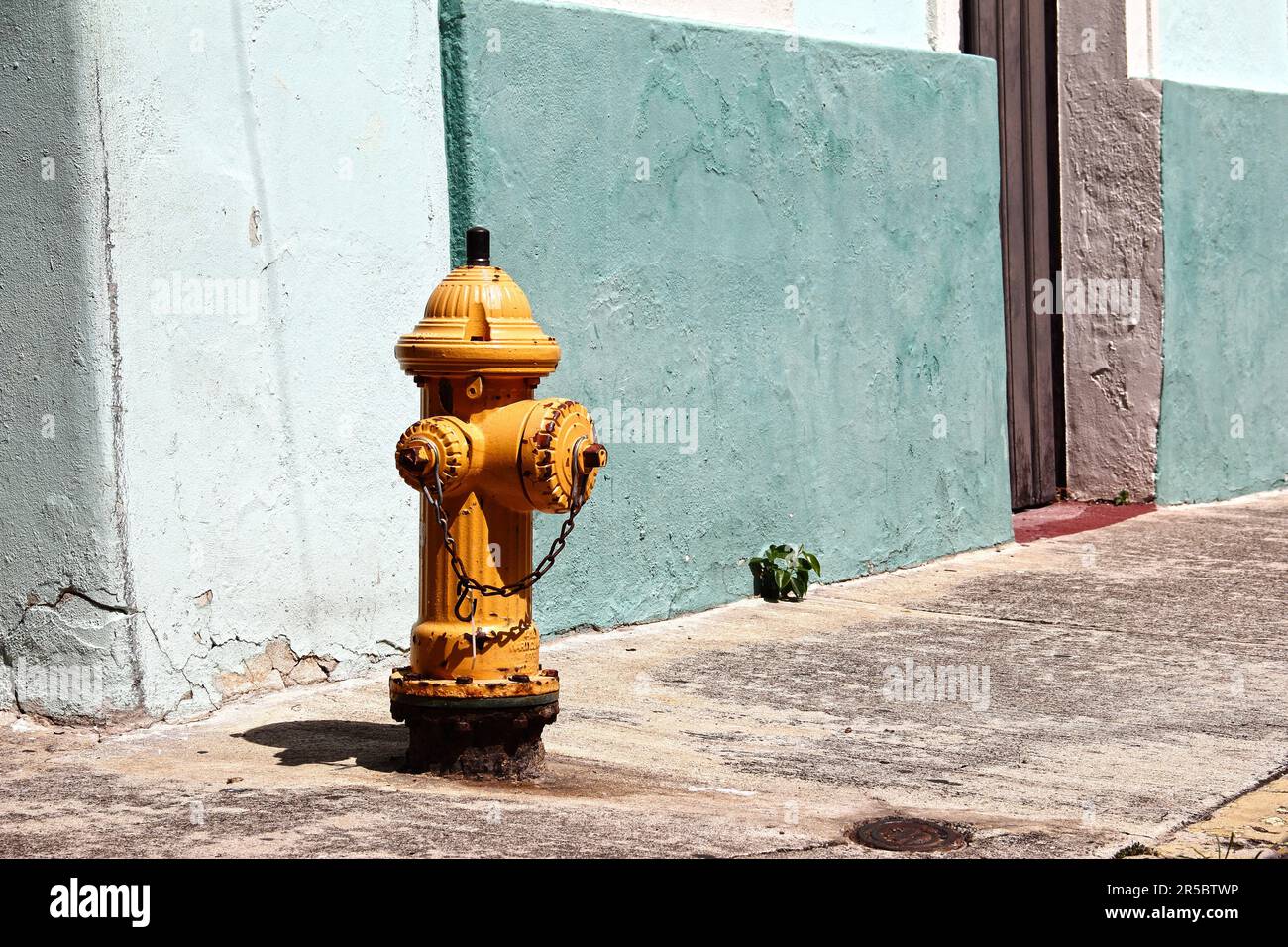 A red fire hydrant stands in front of an old, yellow-bricked building ...