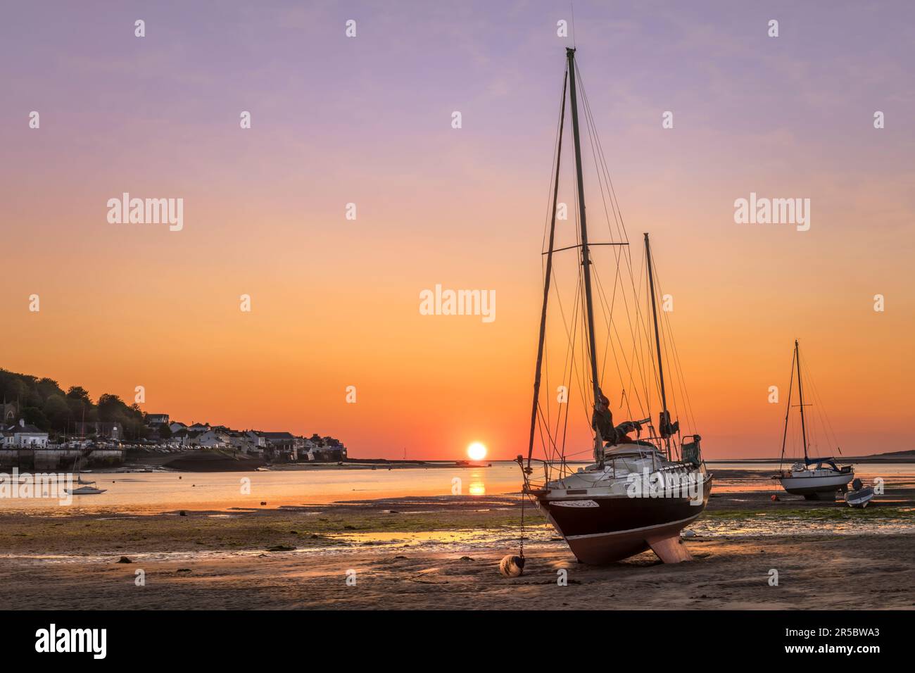 Instow beach on the last day of May. The sun touches the horizon, as ...