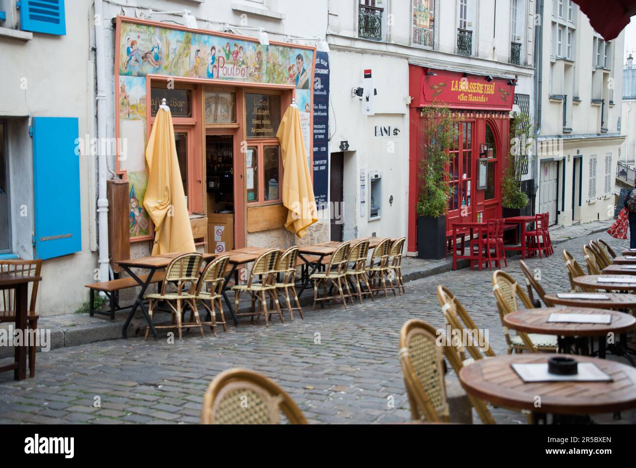 An outdoor empty cafe with tables arranged along a sidewalk in front of ...