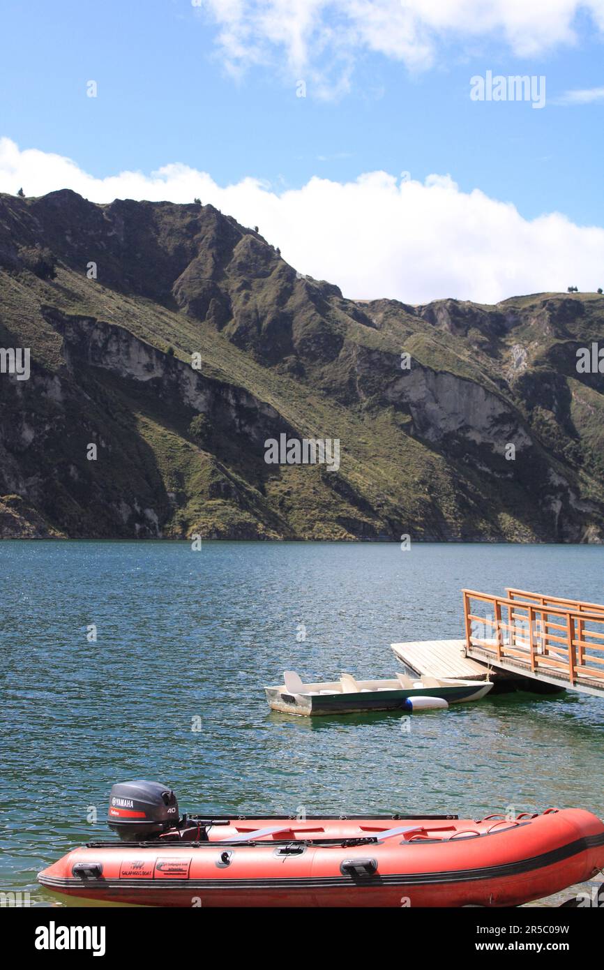 A red inflatable raft boat is docked at a pier in front of a ...