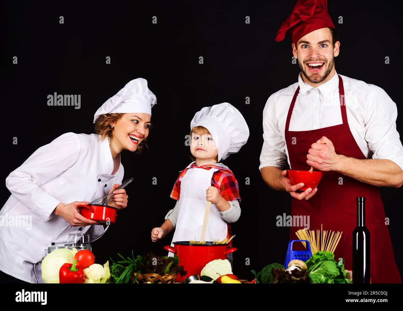 Happy family in chef uniform preparing breakfast, dinner or supper ...