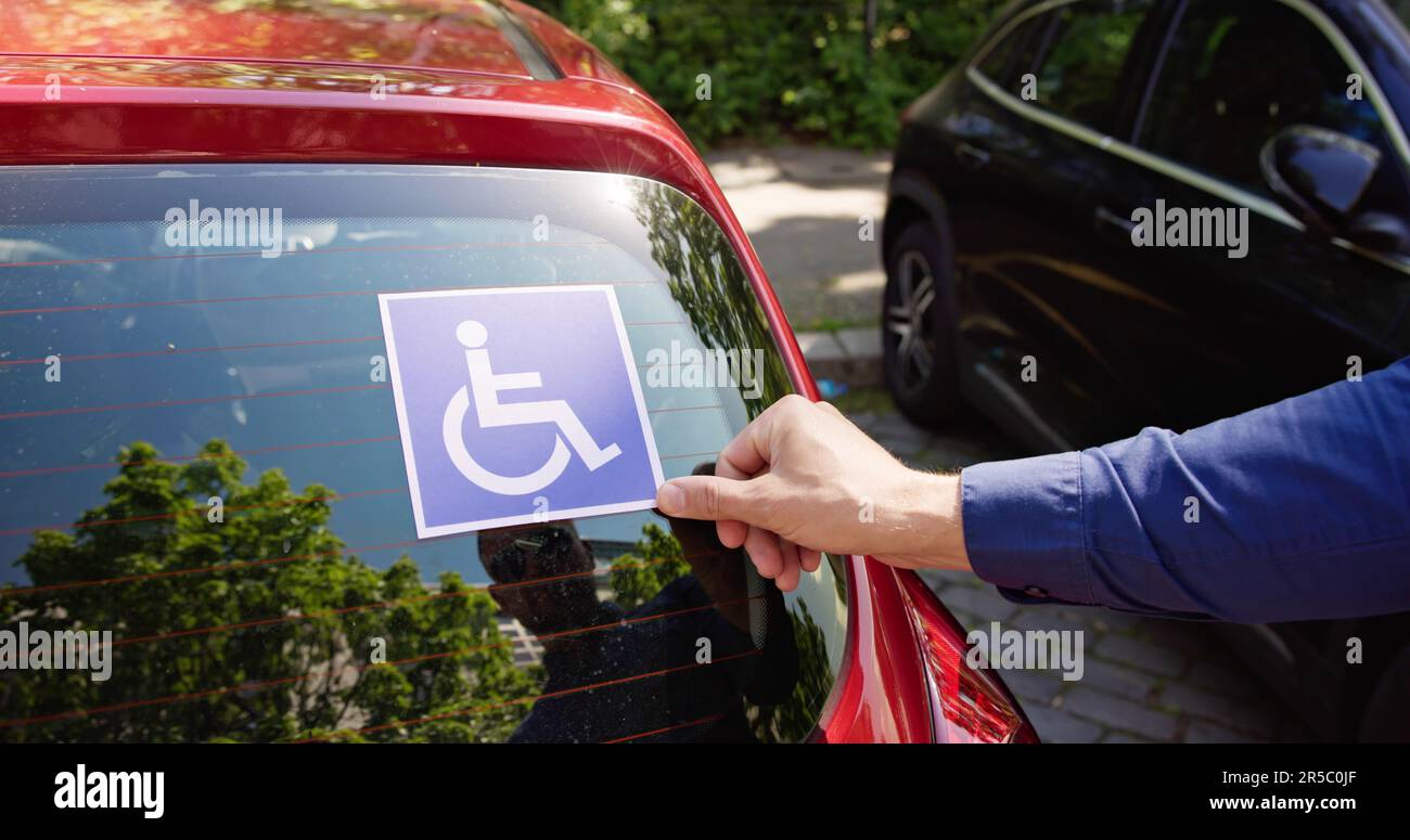 Driver Putting Wheelchair Sticker Sign On Car Vehicle Stock Photo - Alamy