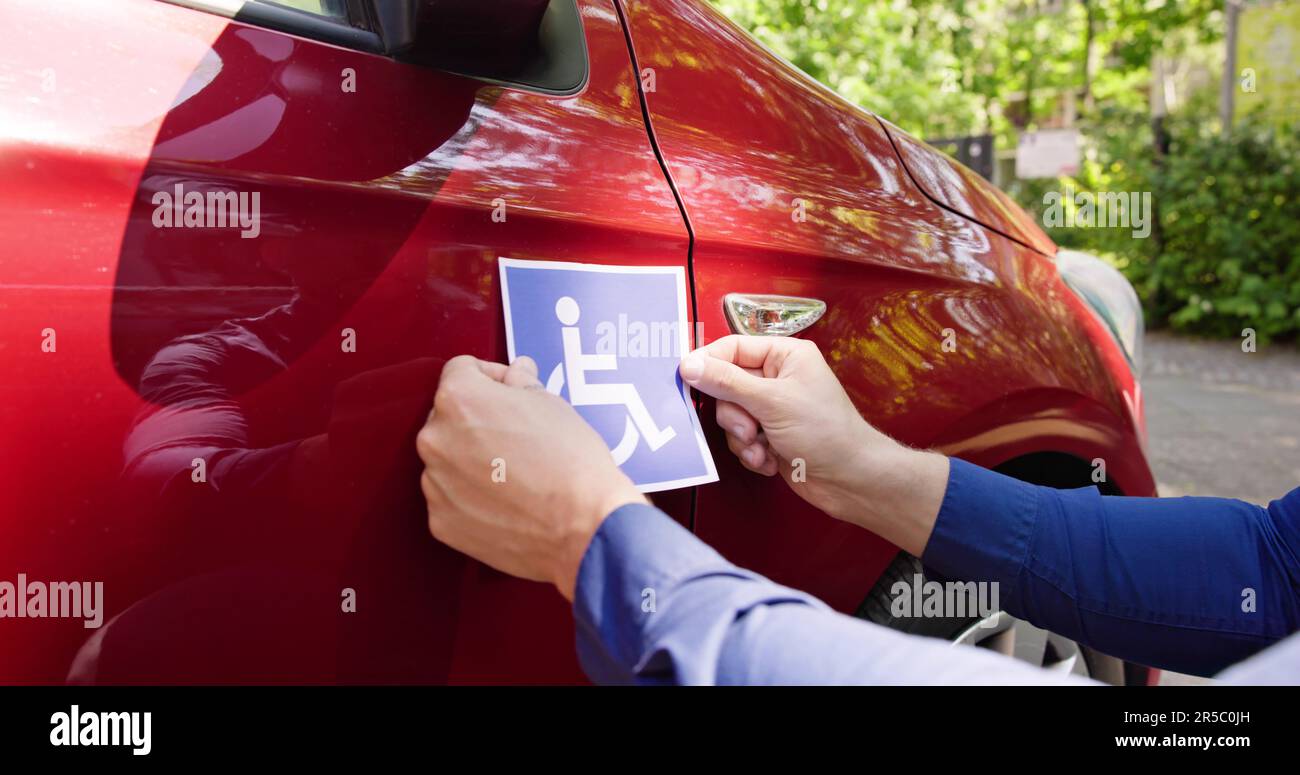 Driver Putting Wheelchair Sticker Sign On Car Vehicle Stock Photo - Alamy