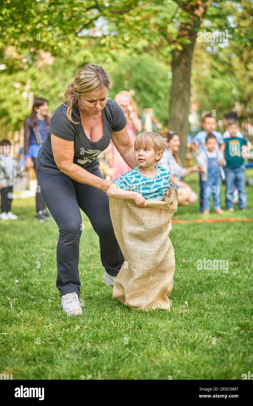 The mother helping her child during an outdoor jumping bag competition ...