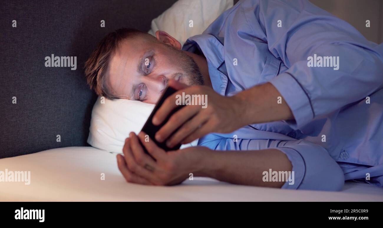 Man Lying On Bed Using Mobile Phone At Night Stock Photo - Alamy