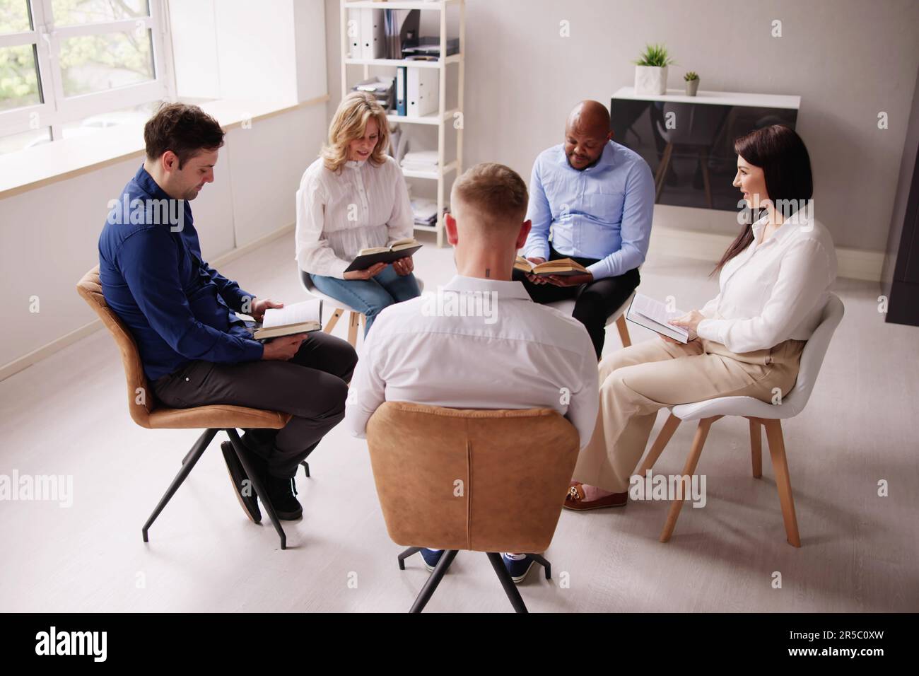 Group Of People Sitting On Chair In Circle Reading Bibles Stock Photo ...