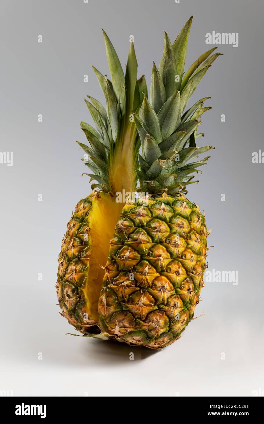 A whole pineapple, halved in the middle with a view of the juicy flesh ...