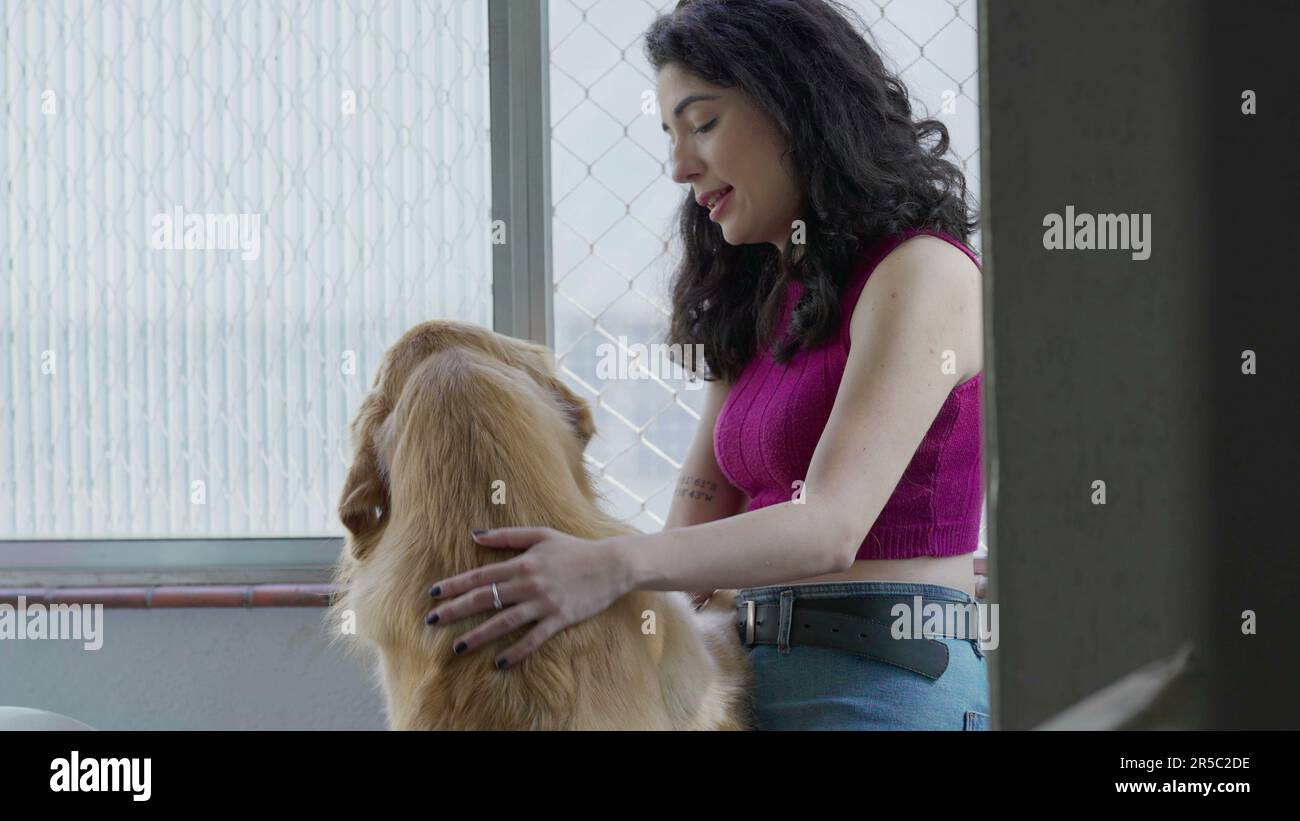 A woman in her 30s bonding with her Golden Retriever at home, captured ...