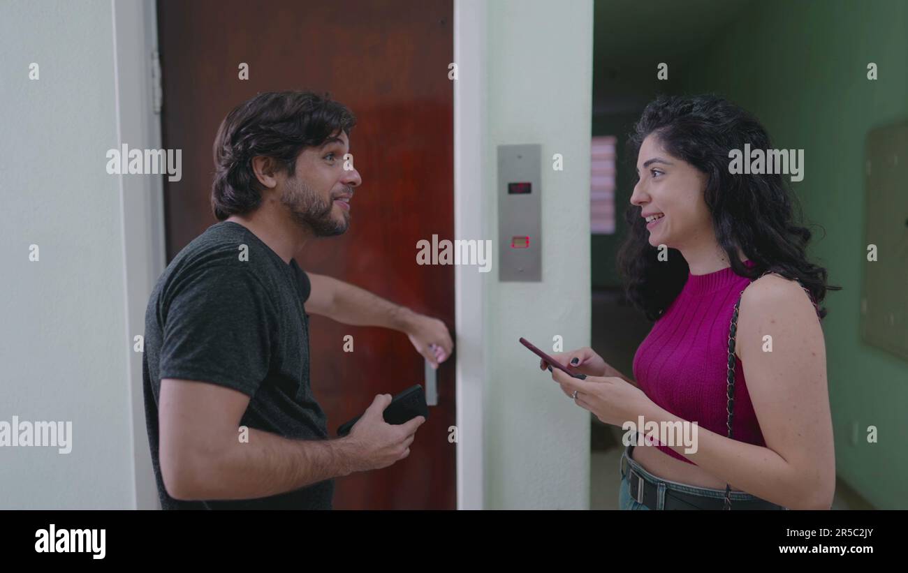 Couple going out waiting by elevator building holding their phones. Man ...