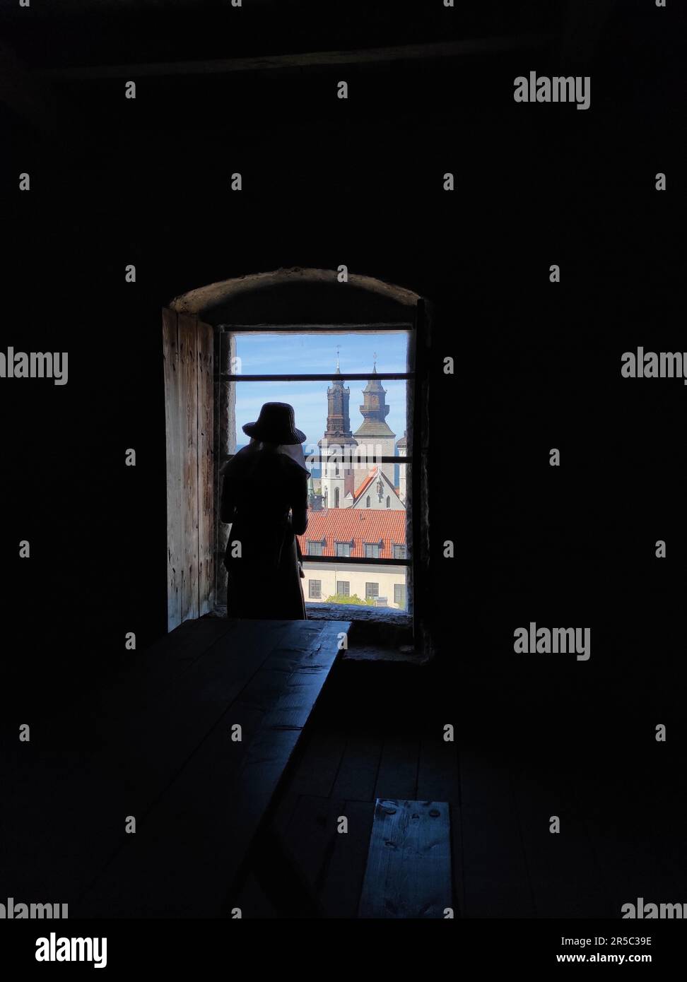 A silhouetted figure is seen standing in an illuminated window in the ...