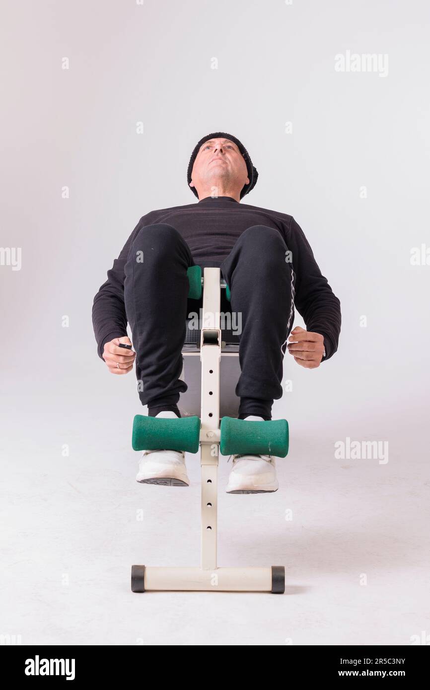 A Caucasian male doing sit up exercise with machine against a white ...