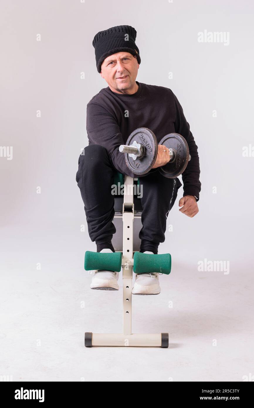 A Caucasian man sitting on the sit up excerside machine and doing ...