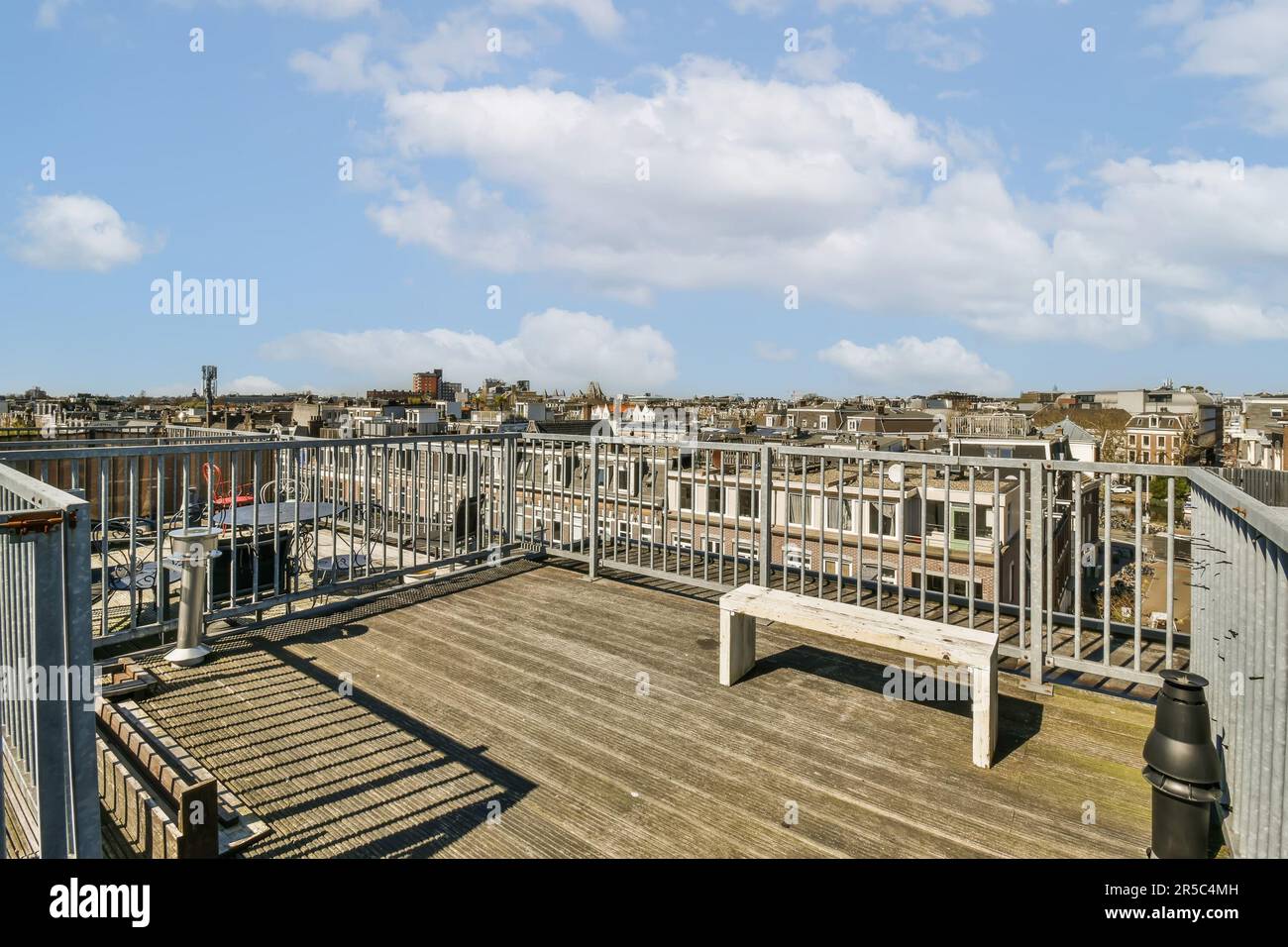 a rooftop with lots of buildings in the distance and blue sky above it ...
