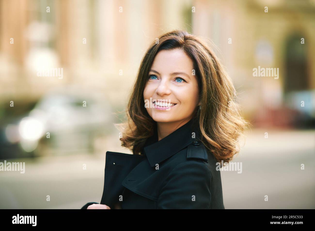 Outdoor portrait of beautiful 40 year old woman wearing black coat ...