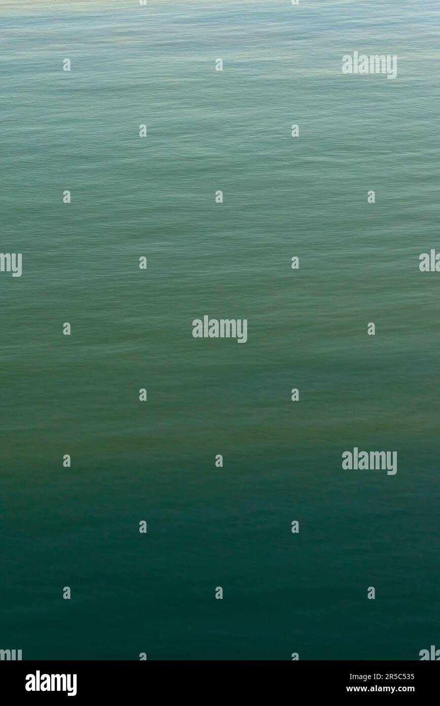 A vertically oriented photo of a beautiful calm sea and sky at sunrise ...