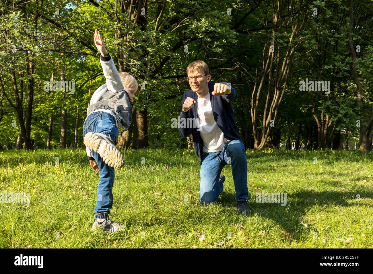 Father teaches little son self defense, fighting in park, meadow ...