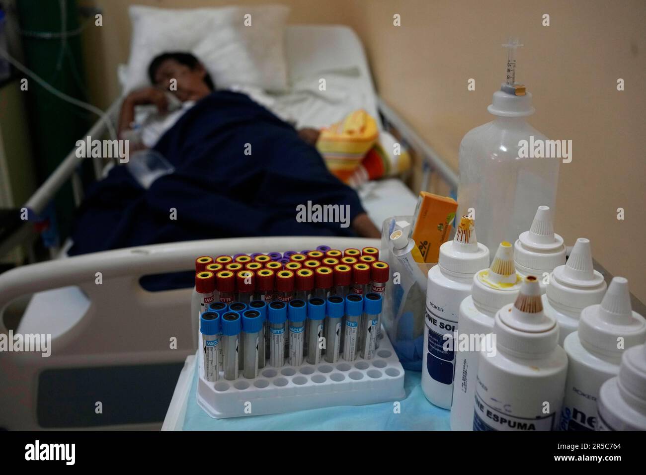Vials for dengue tests sit on a tray near a patient suffering dengue ...