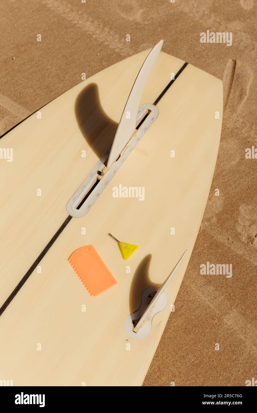 A high-resolution shot of an orange surfboard laying on a sandy beach ...