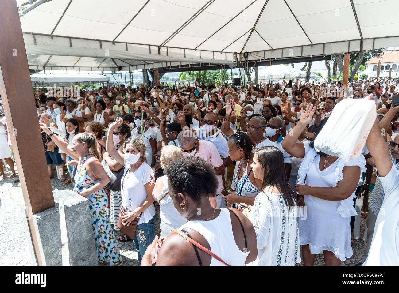 A diverse group of people is gathered in front of a white tent ...