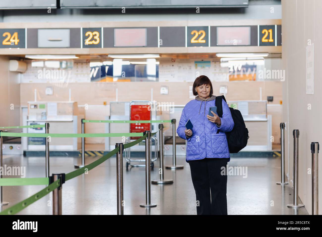Middle aged woman traveler with backpack holds passport, uses cellphone ...