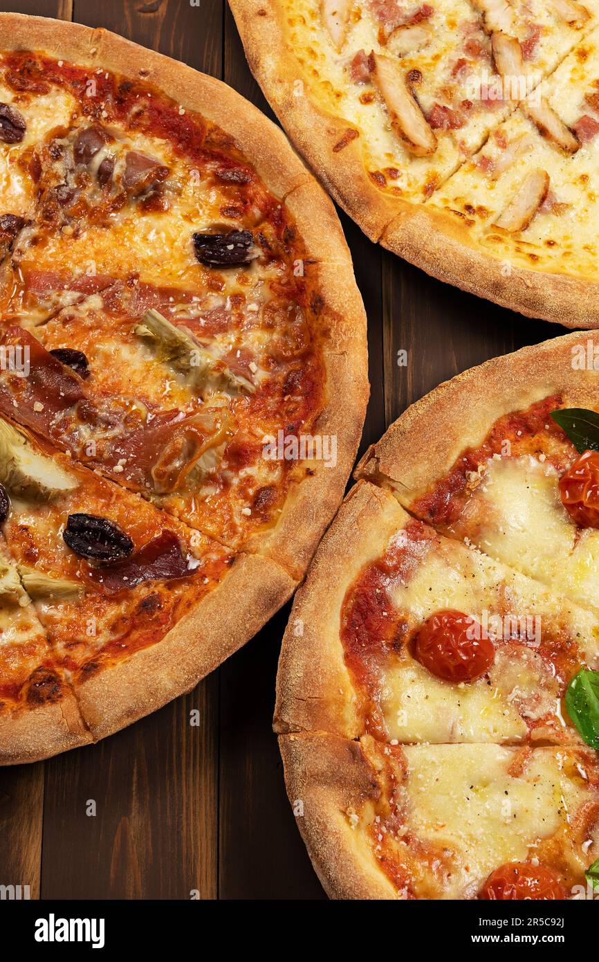 Three different pizzas on wooden background with tomato sauce, mixed ...
