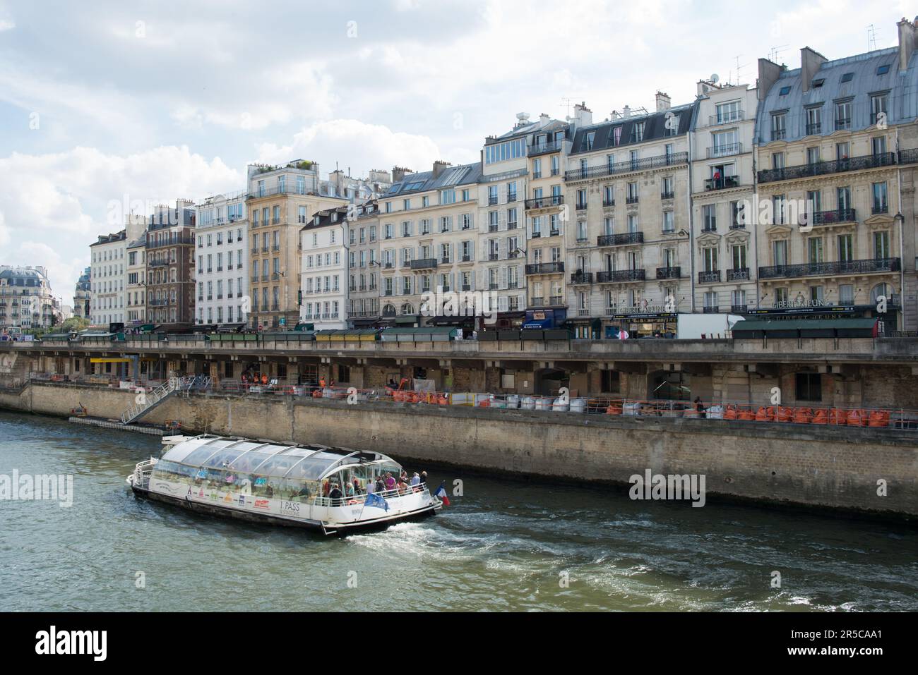 A small boat sailing on the Seine near historic buildings in Paris ...