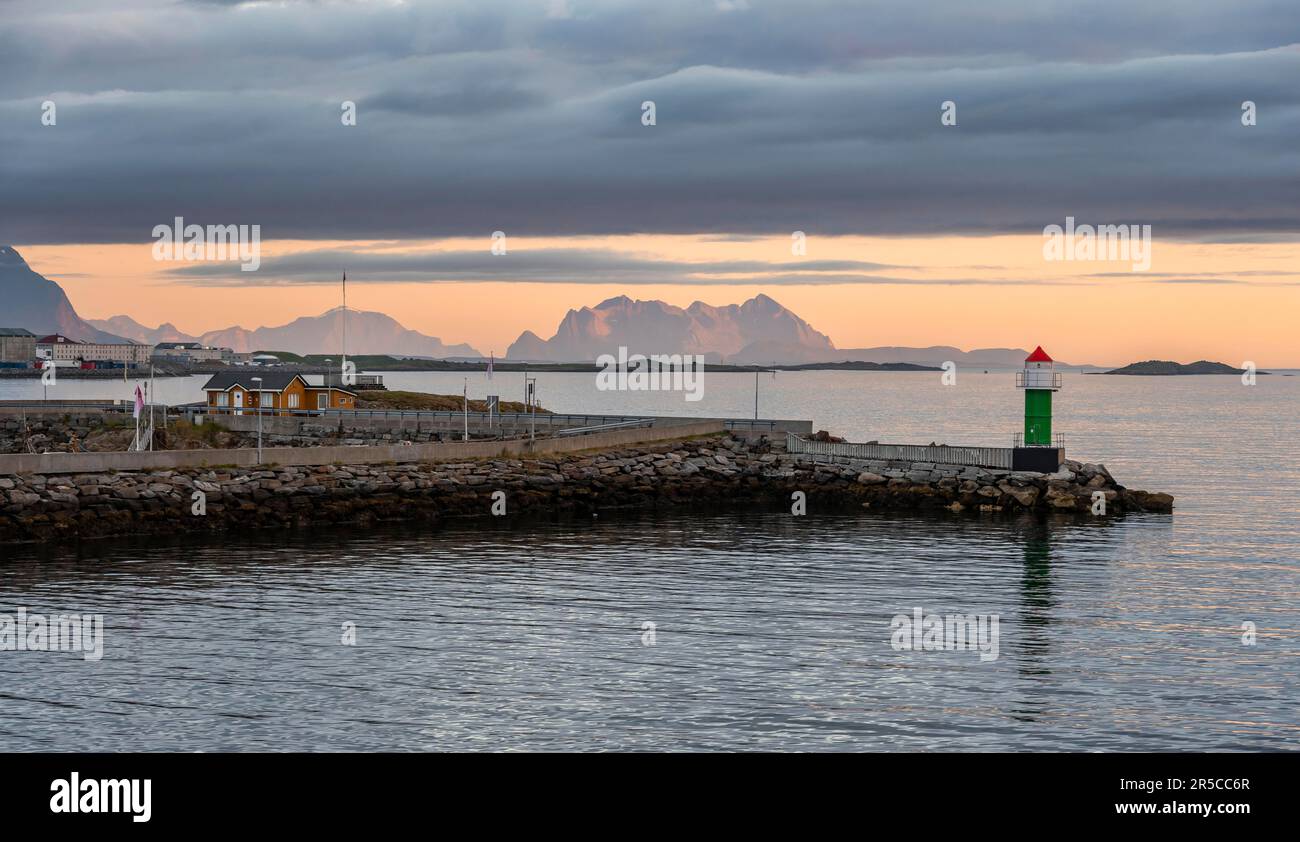 Small lighthouse on an archipelago island, rocky mountain peaks behind ...