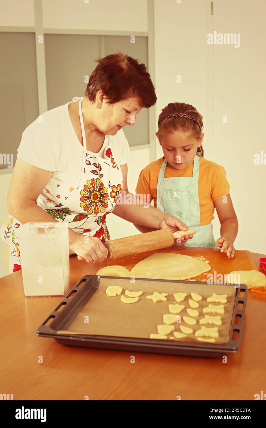 Child and senior woman baking cookies for Christmas in vintage look ...